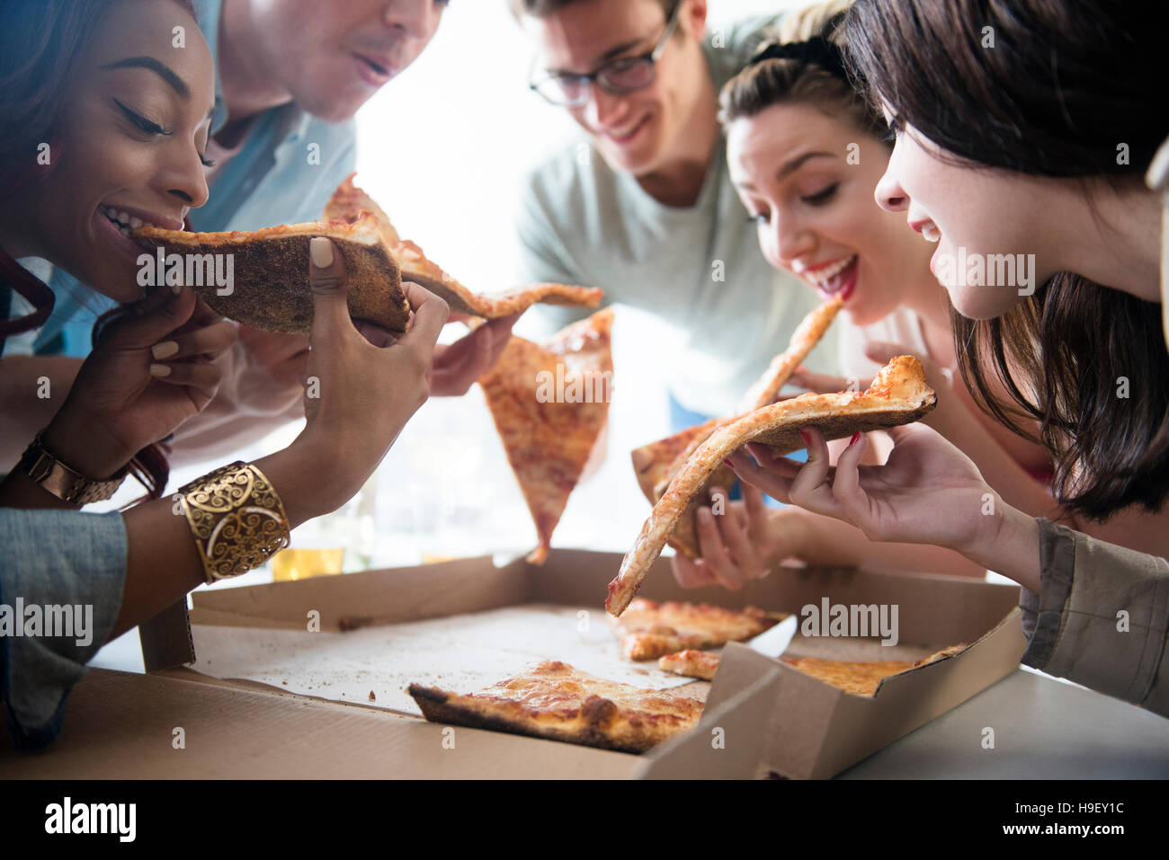 Friends eating slices of pizza Stock Photo - Alamy