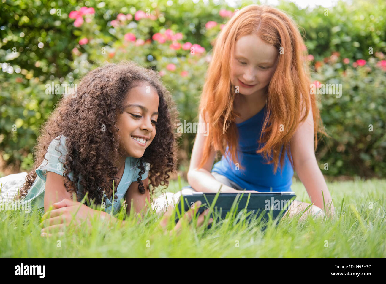 Smiling girls in grass field using digital tablet Stock Photo - Alamy