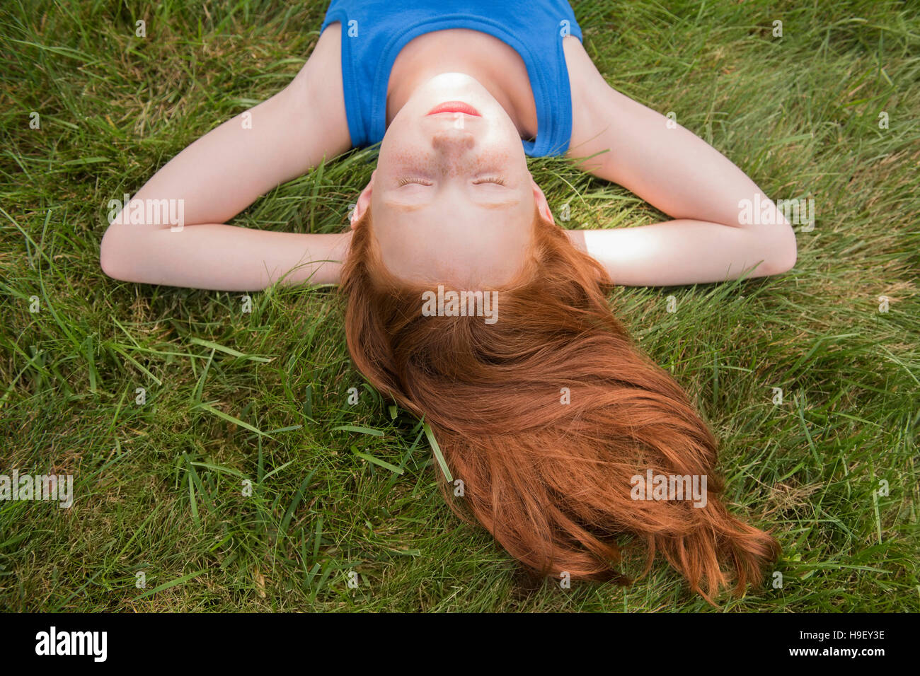 Caucasian girl laying in grass with hands behind head Stock Photo - Alamy
