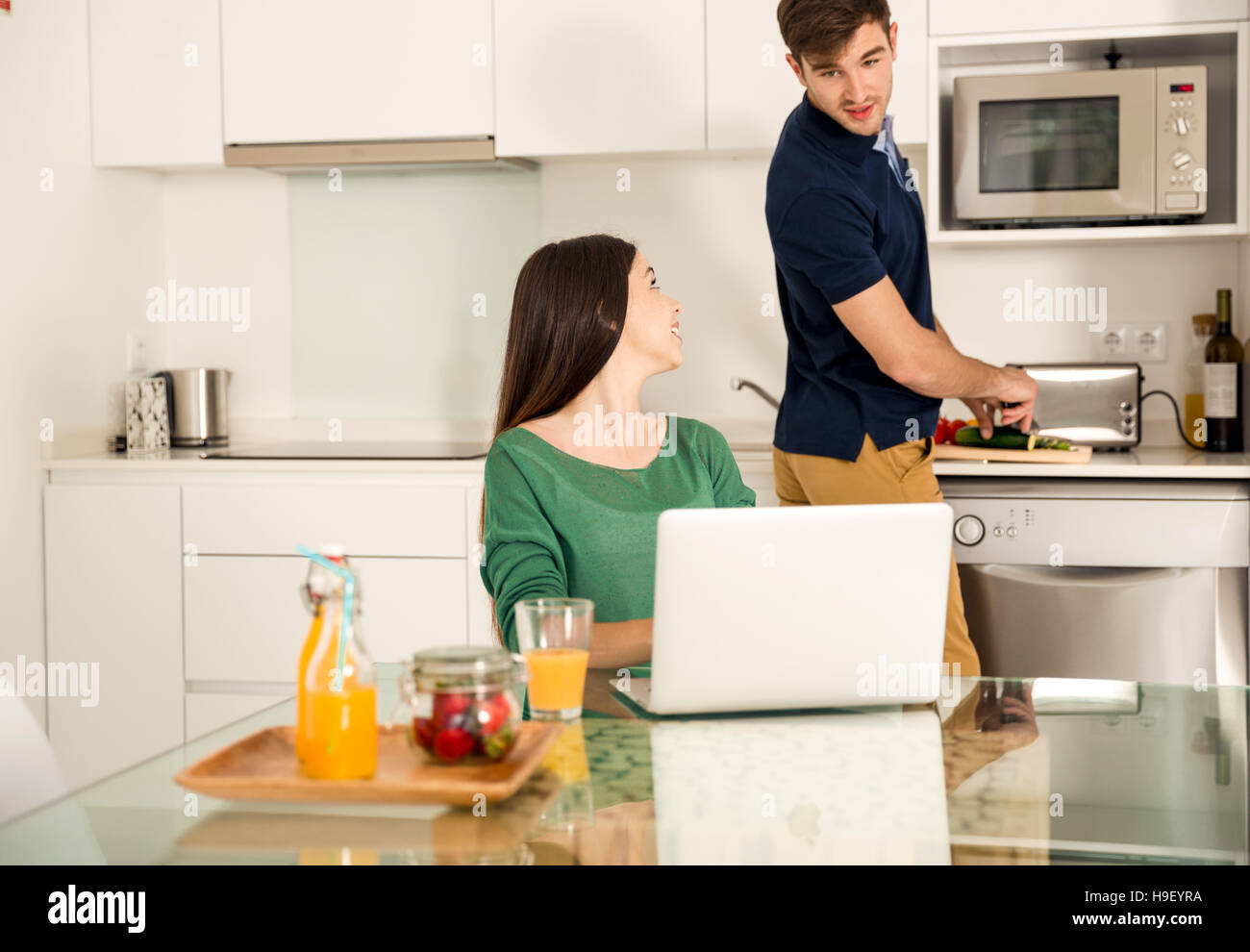 Man cooking while her wife working on a laptop Stock Photo - Alamy