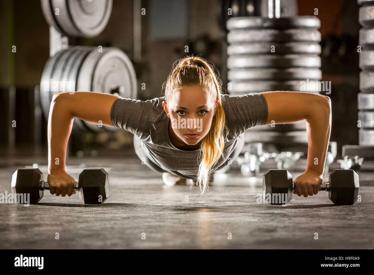 Caucasian woman doing push-up using dumbbells in gymnasium Stock Photo ...