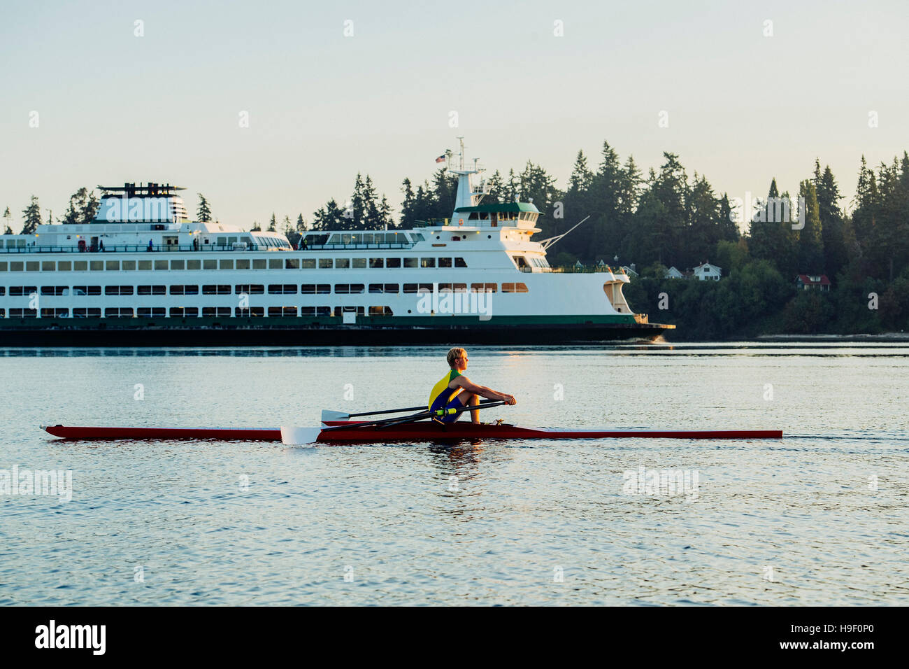 Caucasian man rowing on lake near cruise ship Stock Photo - Alamy