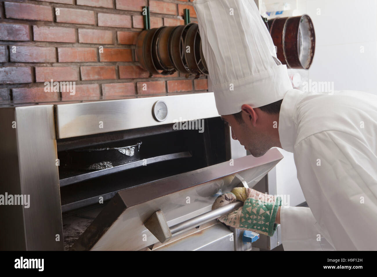 Hispanic chef checking oven Stock Photo - Alamy