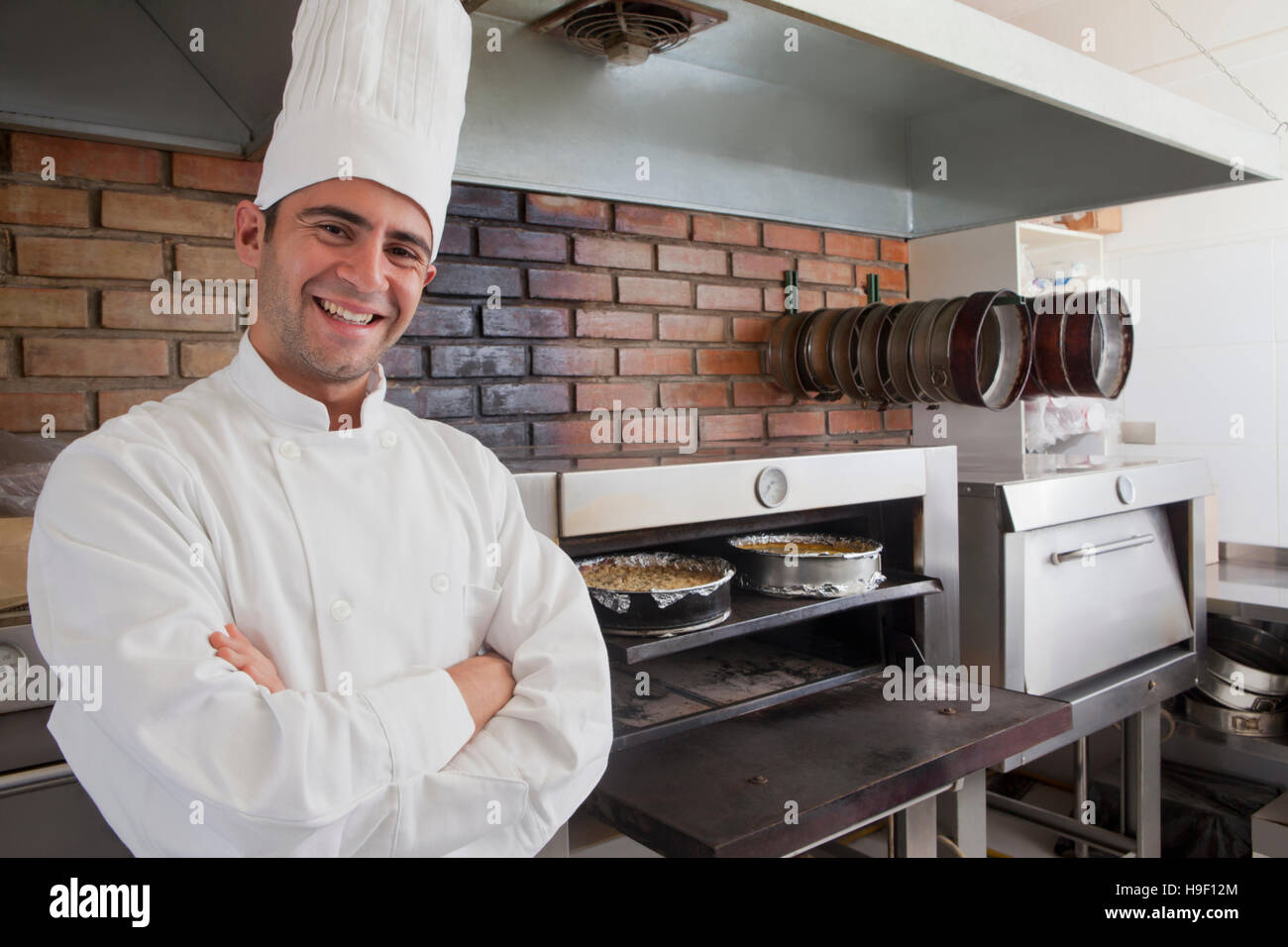 Smiling Hispanic chef posing near cheesecakes in oven Stock Photo - Alamy