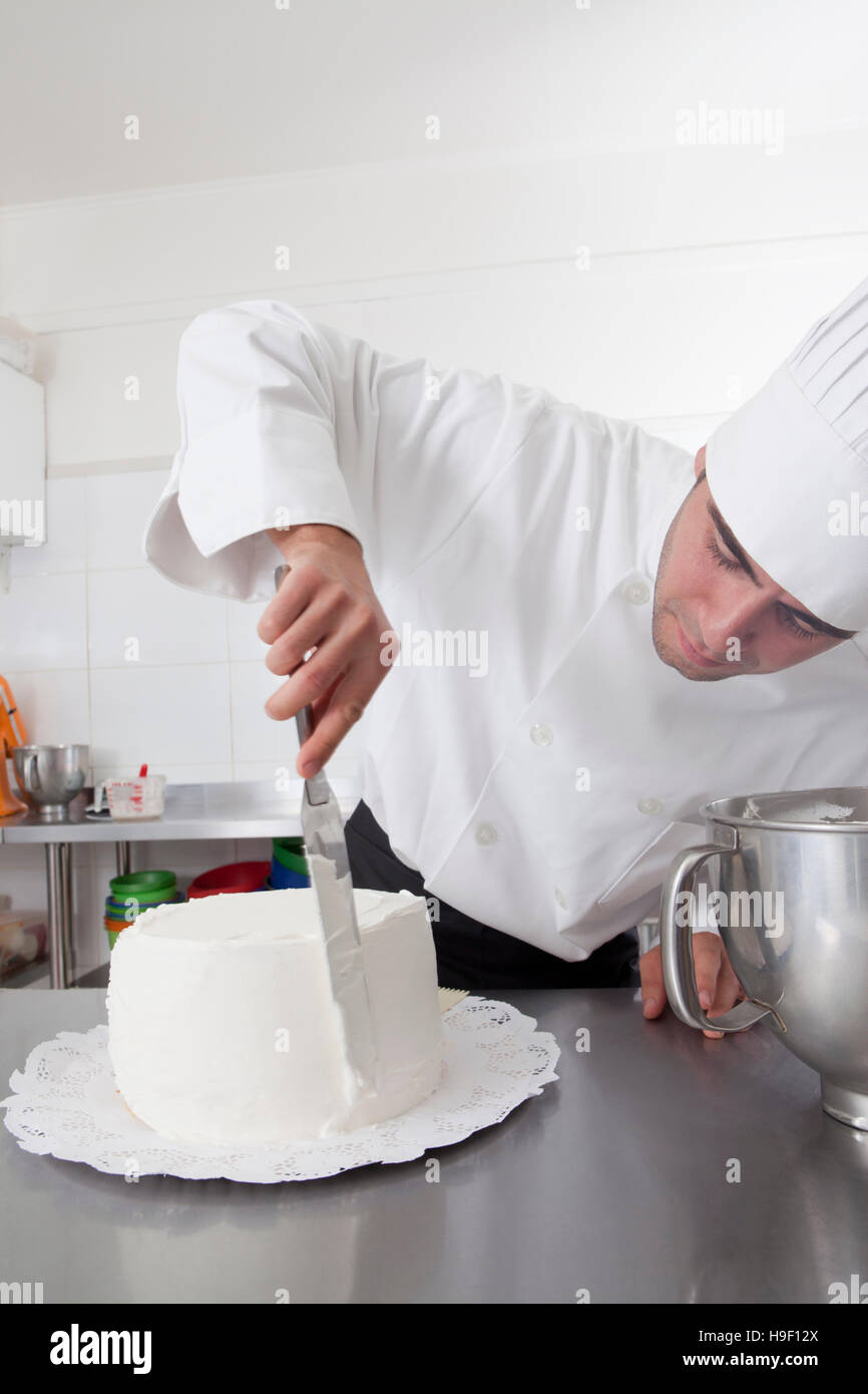 Hispanic chef spreading icing on side of cake Stock Photo - Alamy