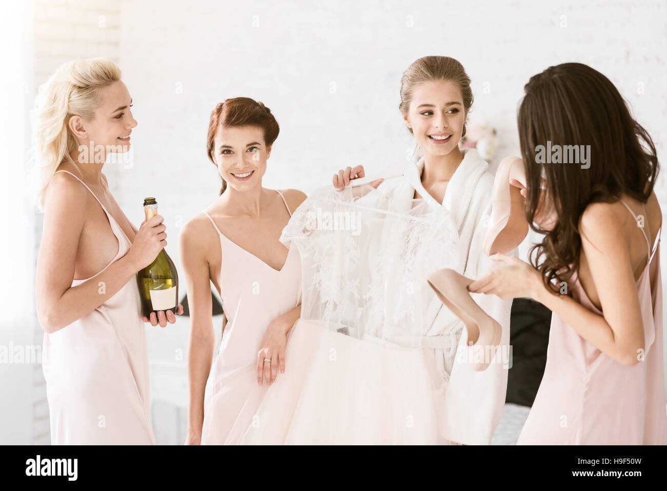Cheerful bridesmaids helping the bride to get ready for wedding Stock ...
