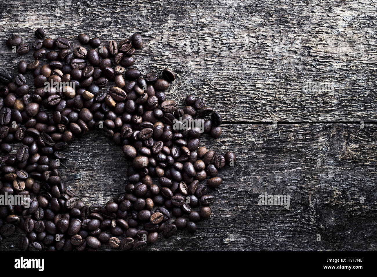 Assorted roasted coffee beans on a rustic, weathered textured driftwood ...