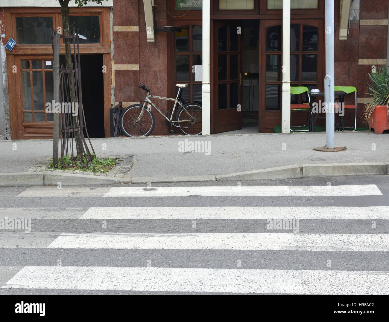 Street with old and scratched bike across it, leaning against the wall ...