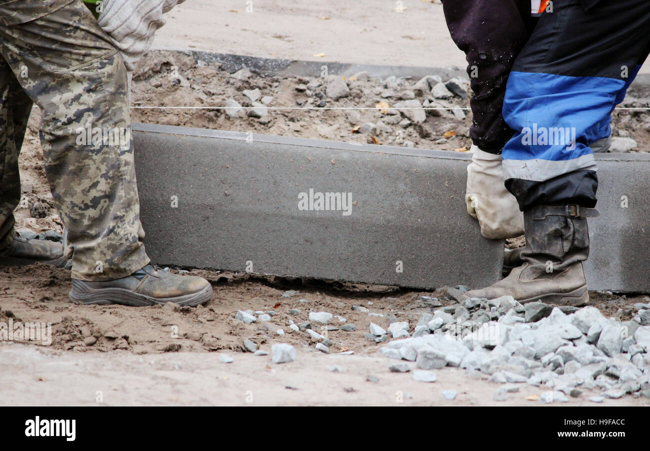 Workers are lifting concrete curb. Concrete kerb installation at ...