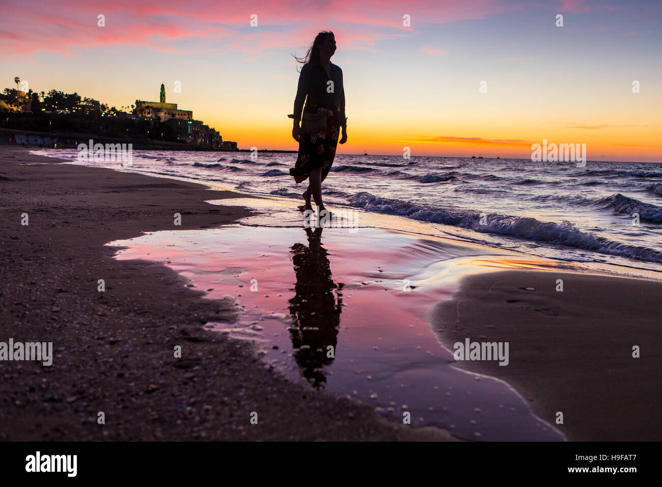 silhouette of woman walking along dusky beach Stock Photo - Alamy