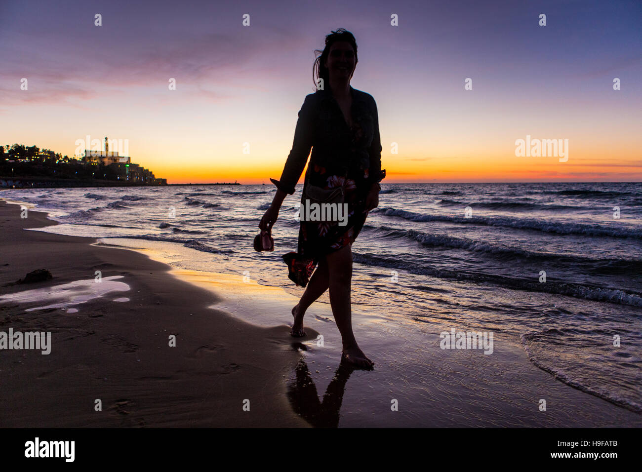 silhouette of woman walking along dusky beach Stock Photo - Alamy