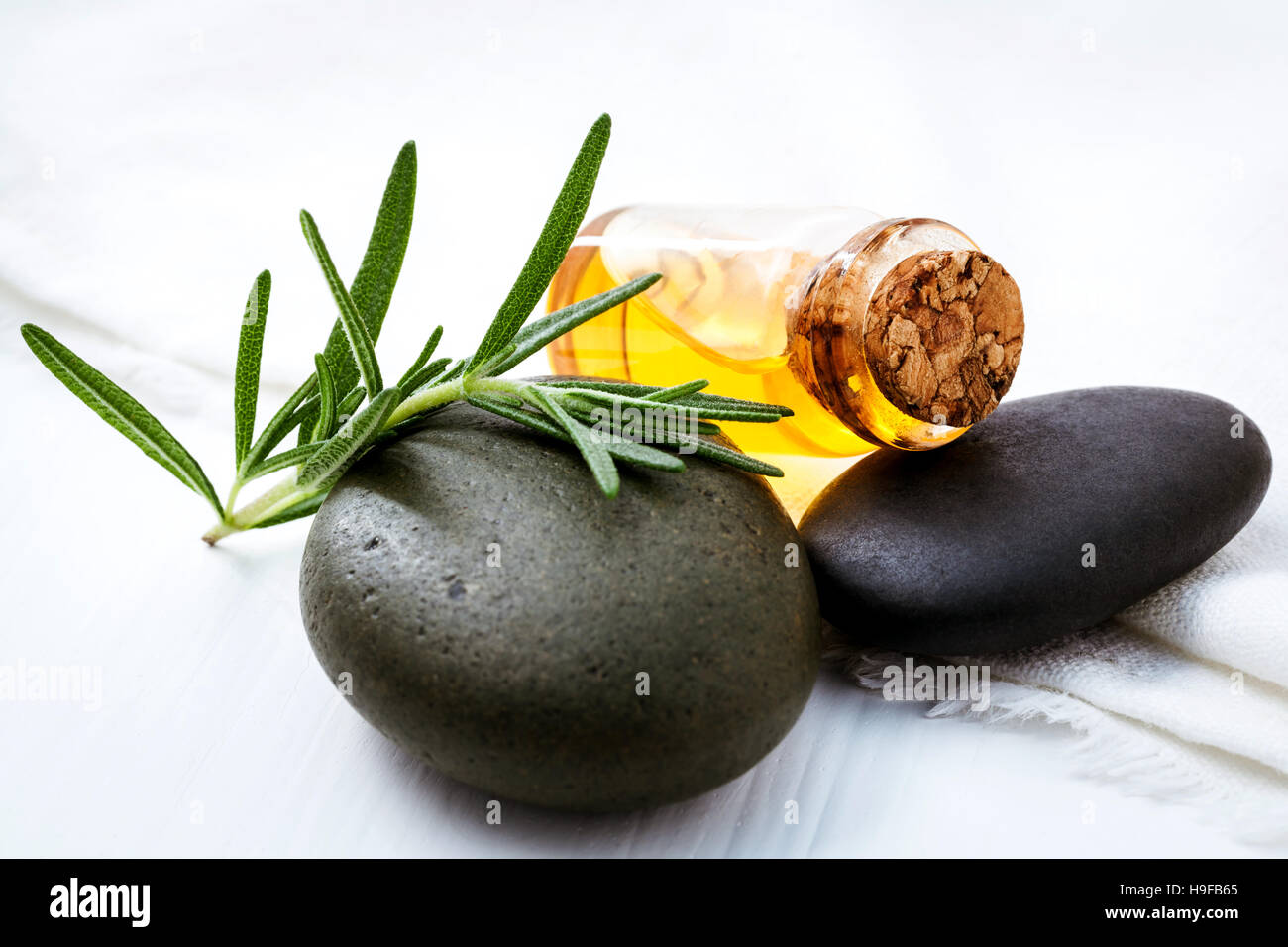Fresh rosemary on spa stone with essential oil setup on white Stock ...