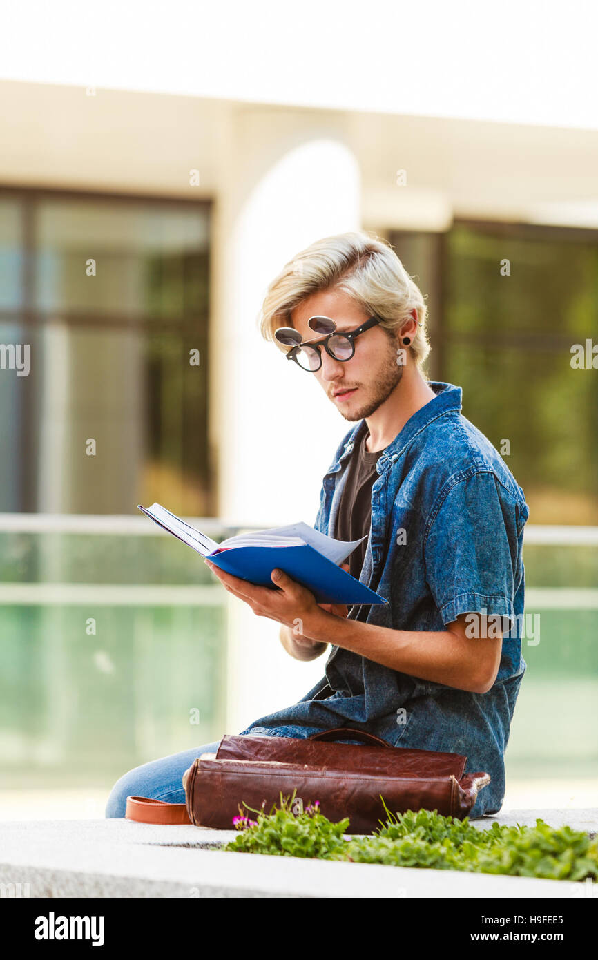 Male fashion, student concept. Guy holding and studying from notebook ...