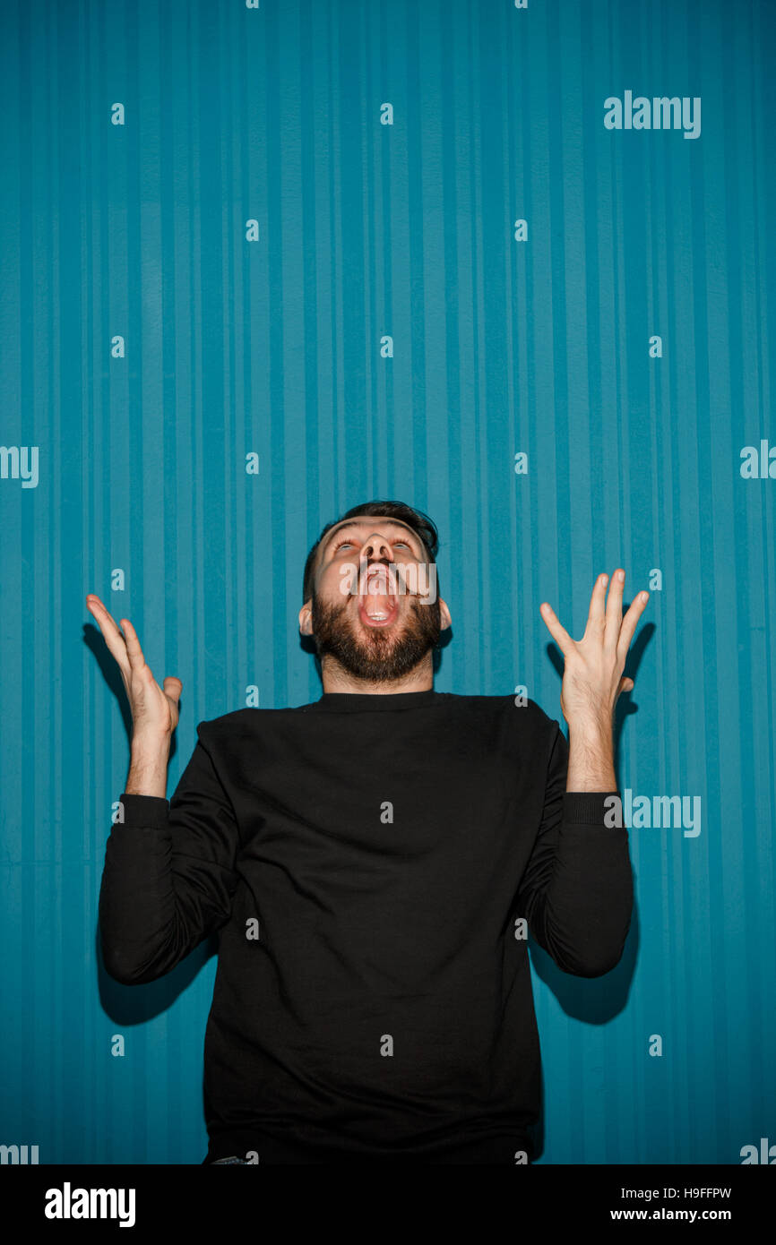 Portrait of young man with shocked facial expression pointing up over ...
