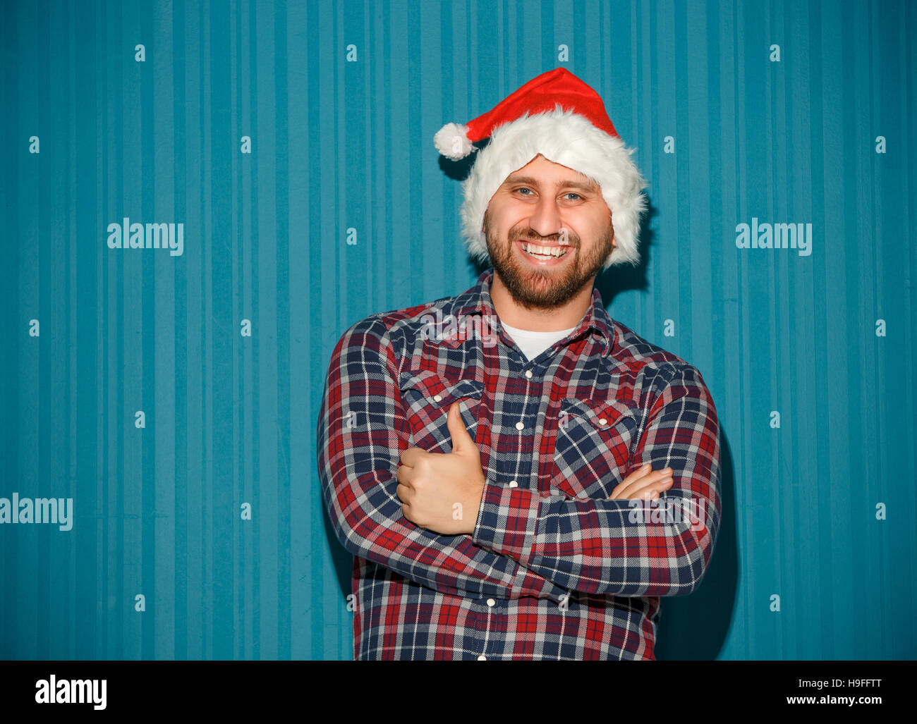 Smiling christmas man wearing a santa hat on the blue studio background ...