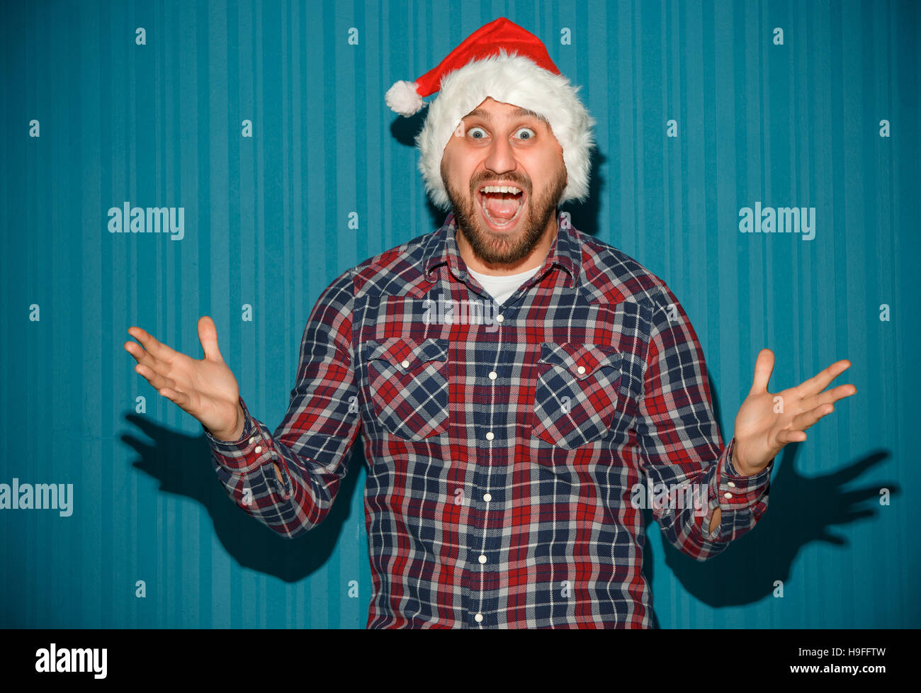 Smiling christmas man wearing a santa hat on the blue studio background ...