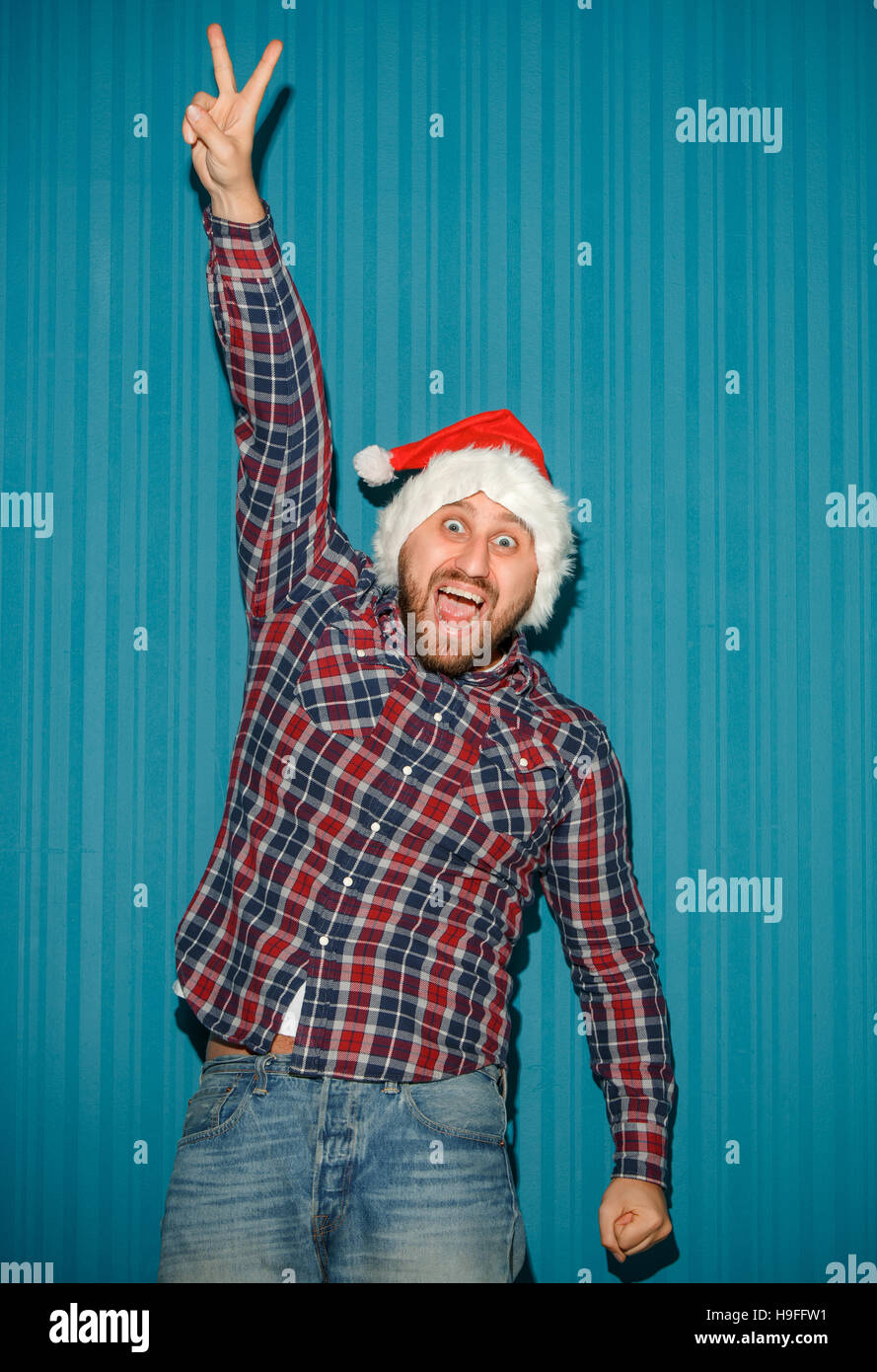 Smiling christmas man wearing a santa hat on the blue studio background ...
