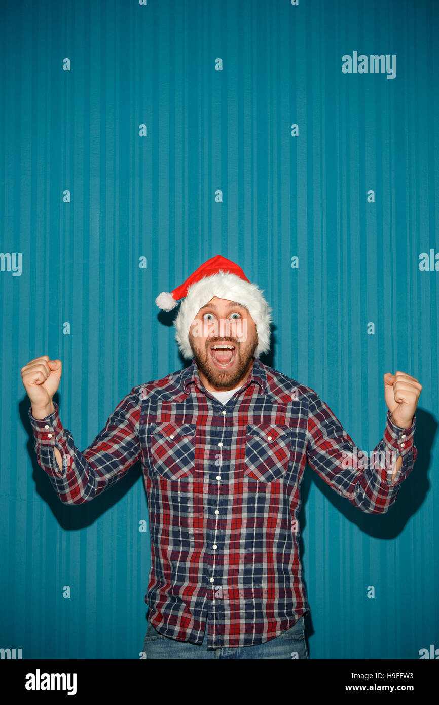 Smiling christmas man wearing a santa hat on the blue studio background ...