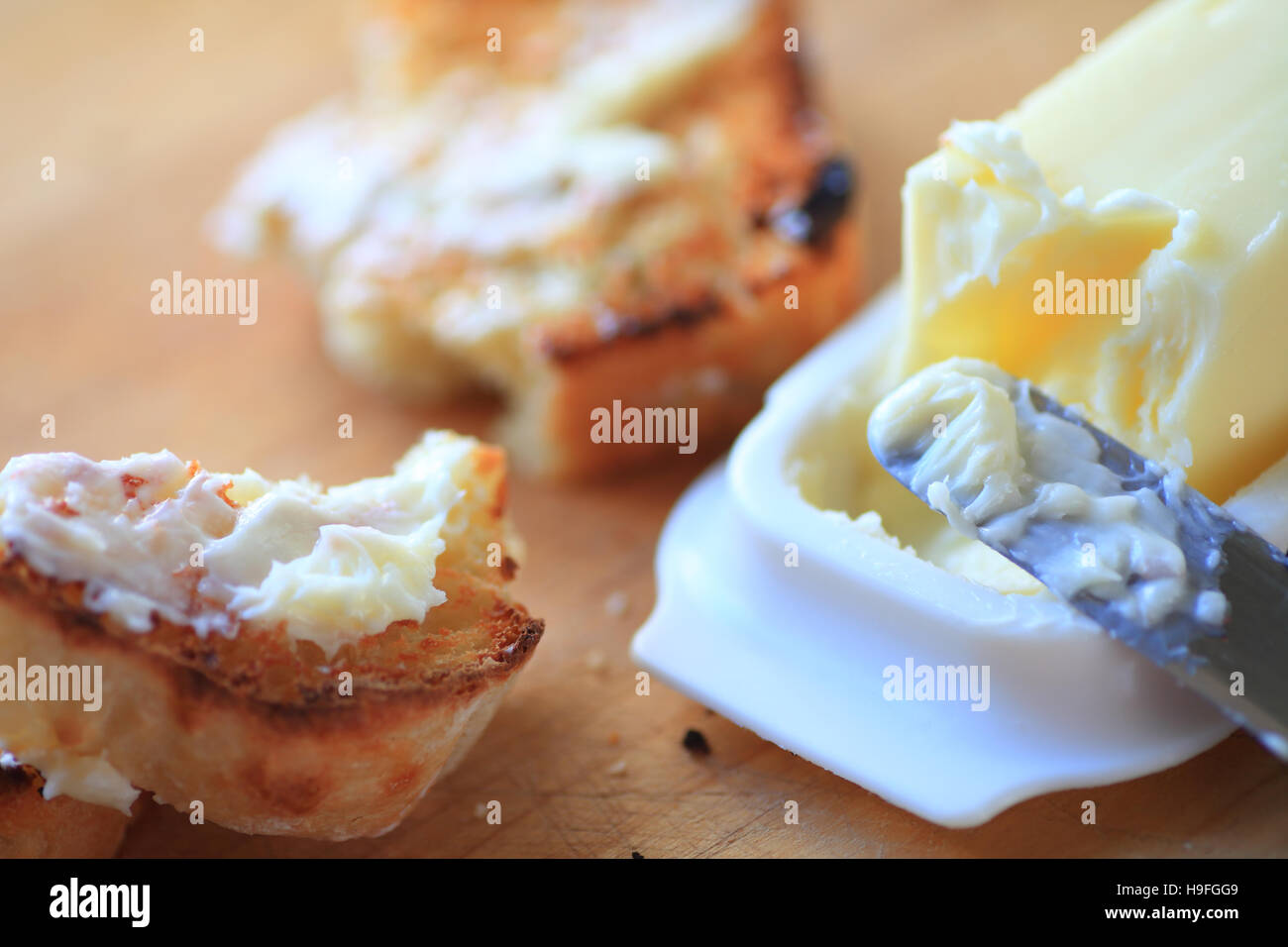 Broken slice of buttered toast with knife and butter dish Stock Photo ...