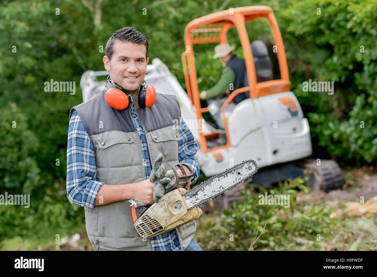 Gardener holding a chainsaw Stock Photo - Alamy