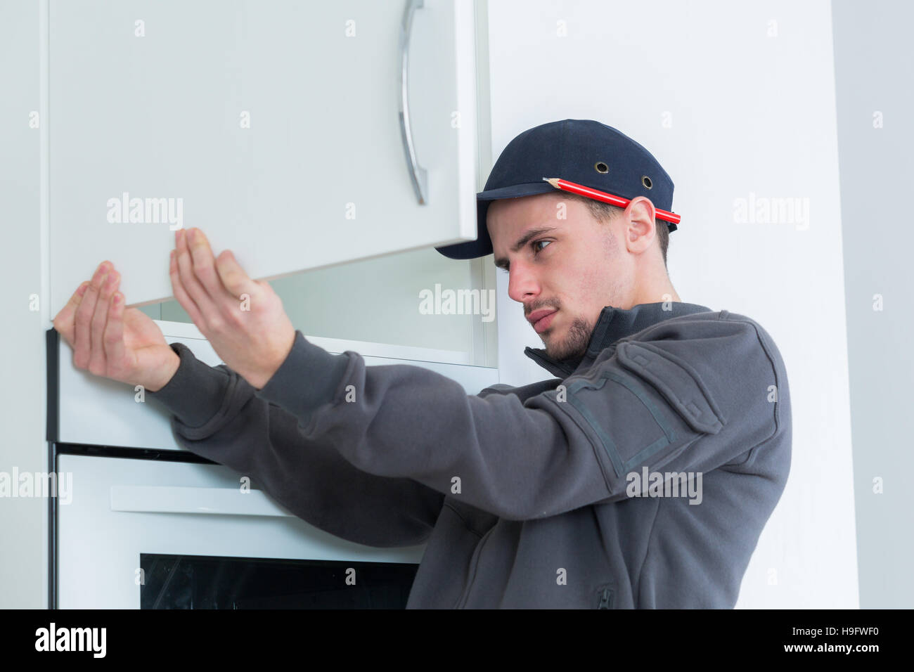 handyman fixing the cupboard in the kitchen Stock Photo - Alamy
