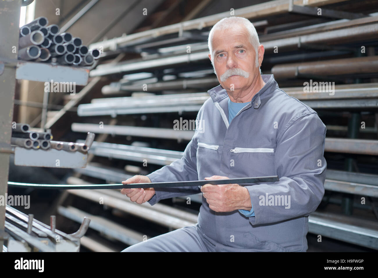 Senior man holding sheet of metal Stock Photo - Alamy