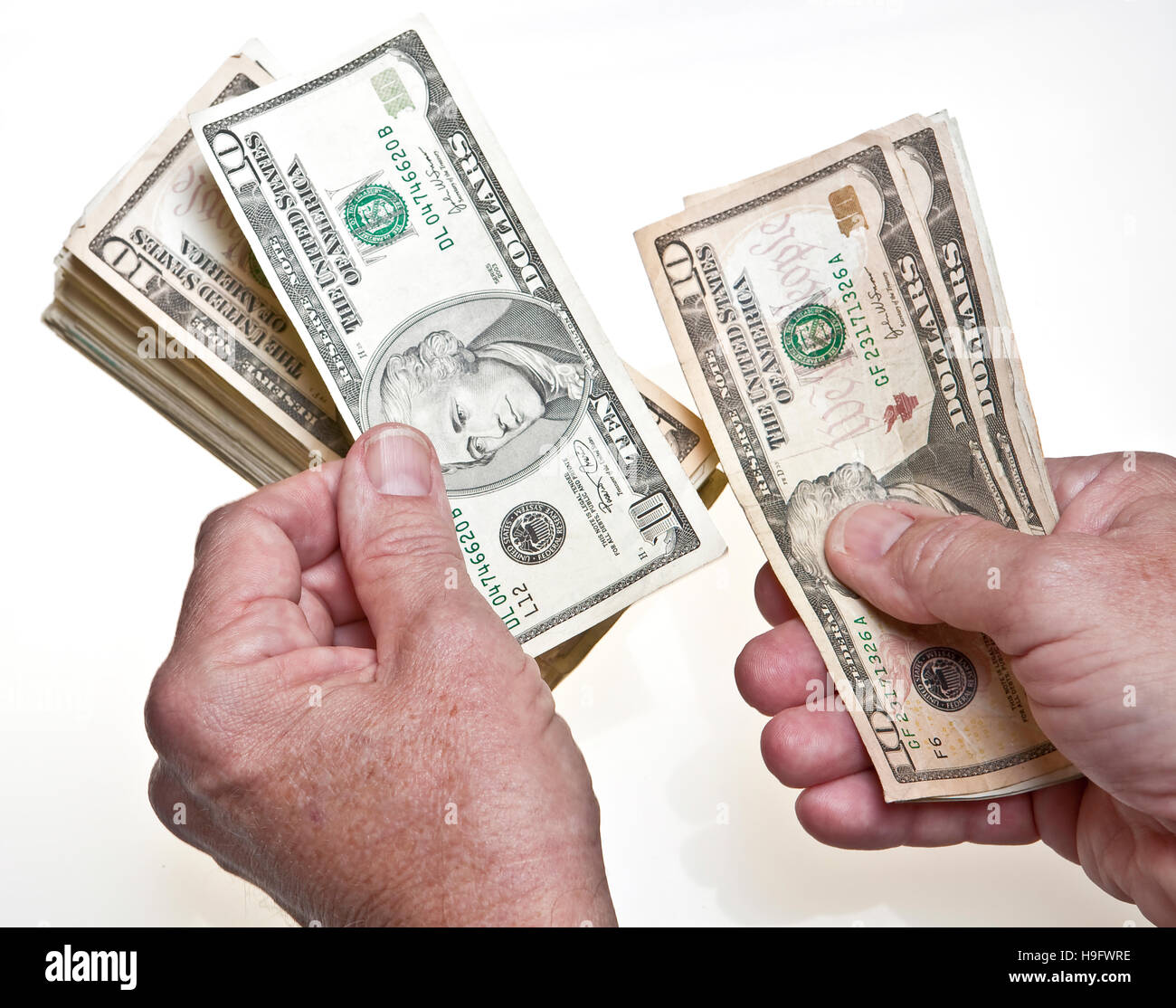 Older man's hands counting ten dollar bills onto a stack on white ...