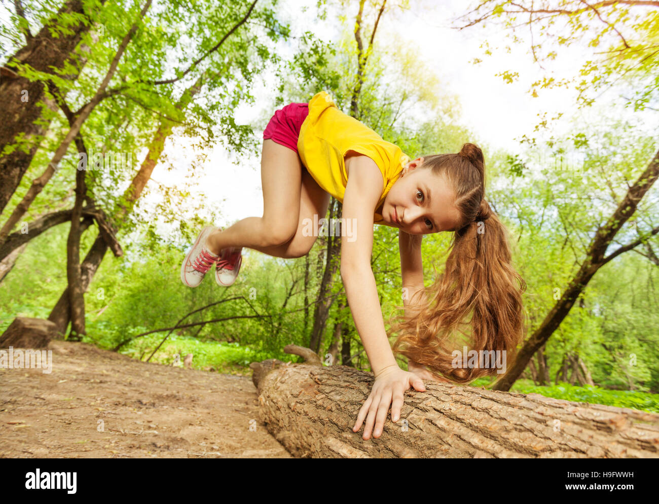 Cute girl jumping over the log in summer forest Stock Photo - Alamy
