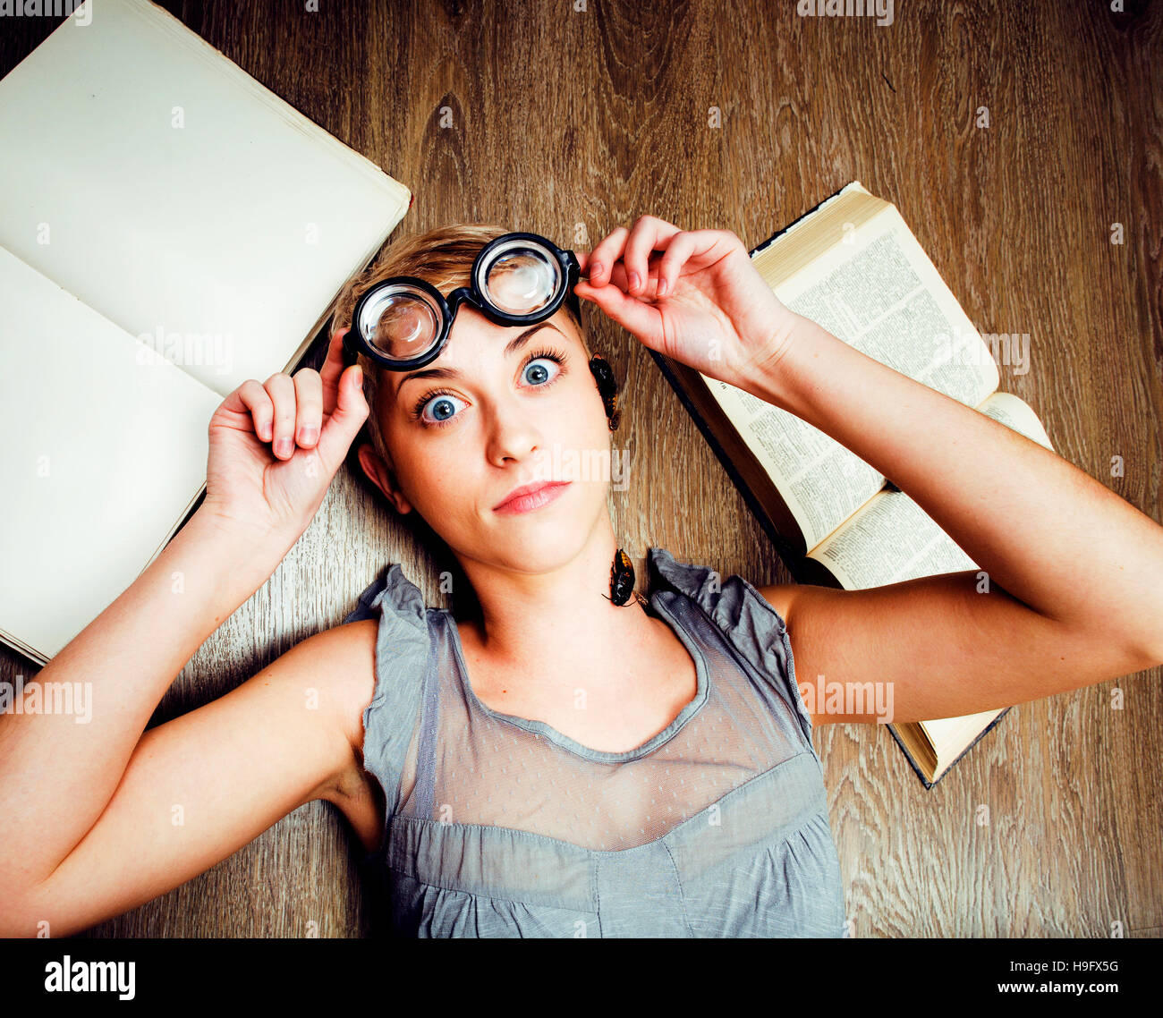 portrait of crazy student girl in glasses with books and cockroaches ...