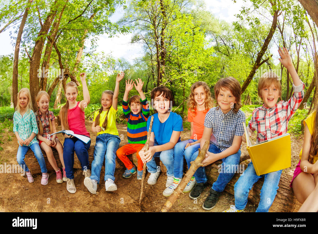 Funny kids sitting on log outdoor and reading book Stock Photo - Alamy