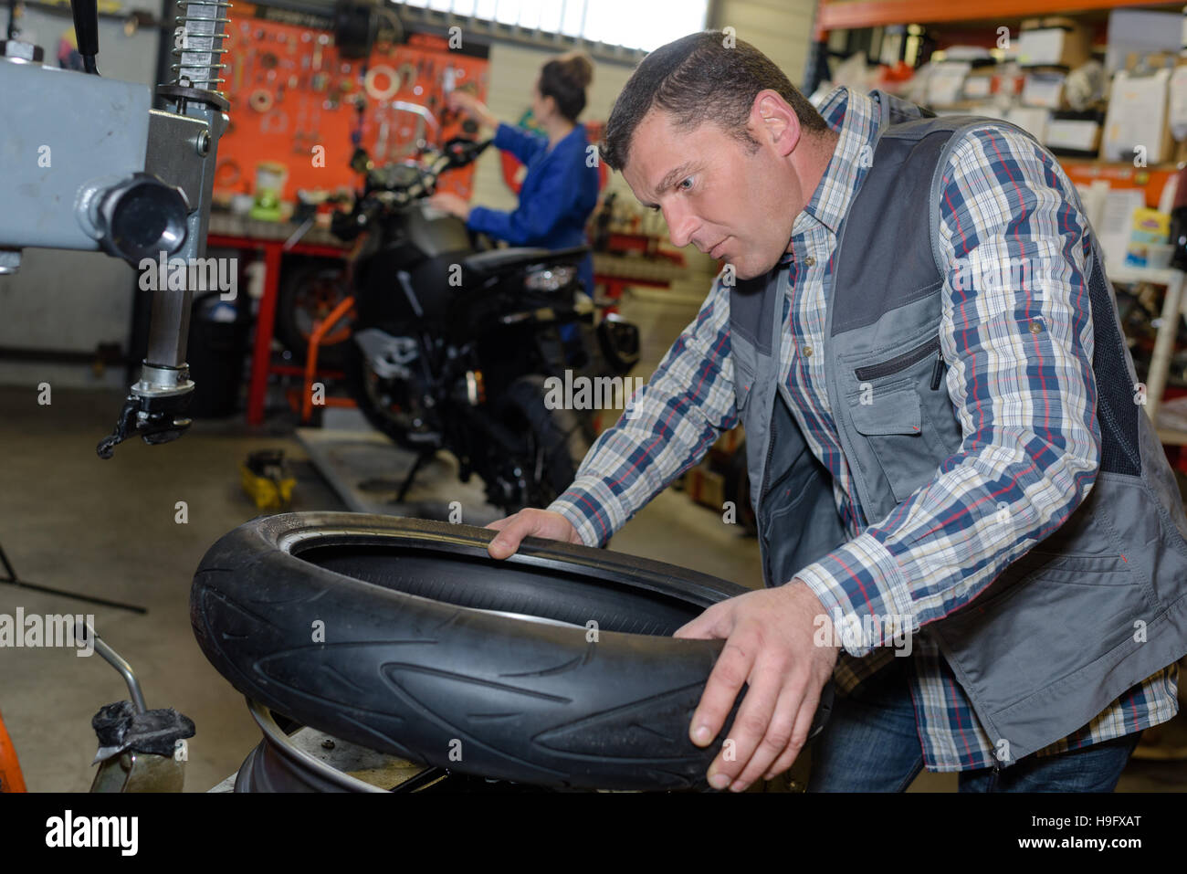 service mechanic with installer replace tyre on wheel in workshop Stock ...