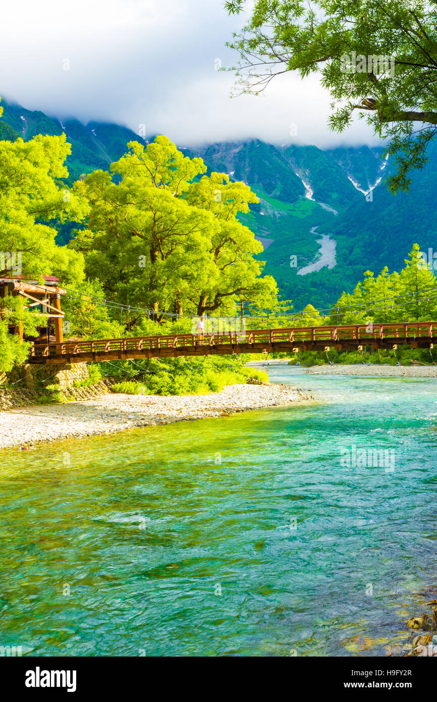 Man crossing Kappa Bridge with Mount Hotaka-dake background during ...