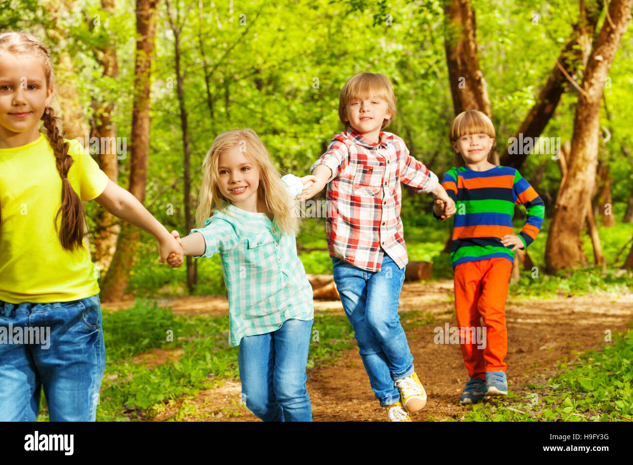 Happy friends running in the forest holding hands Stock Photo - Alamy