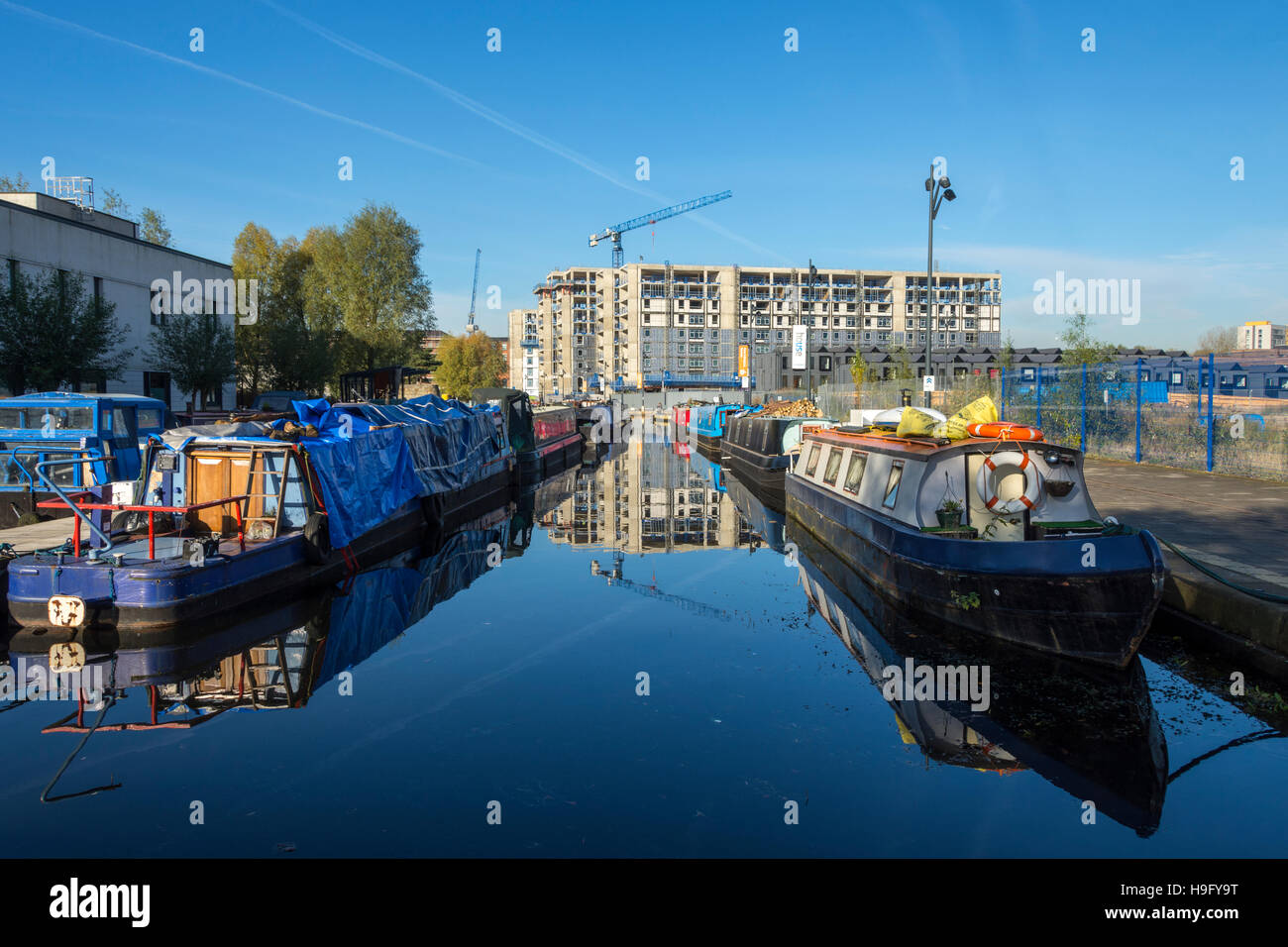 Narrowboats and cranes reflected in the Cotton Field Park marina, New ...