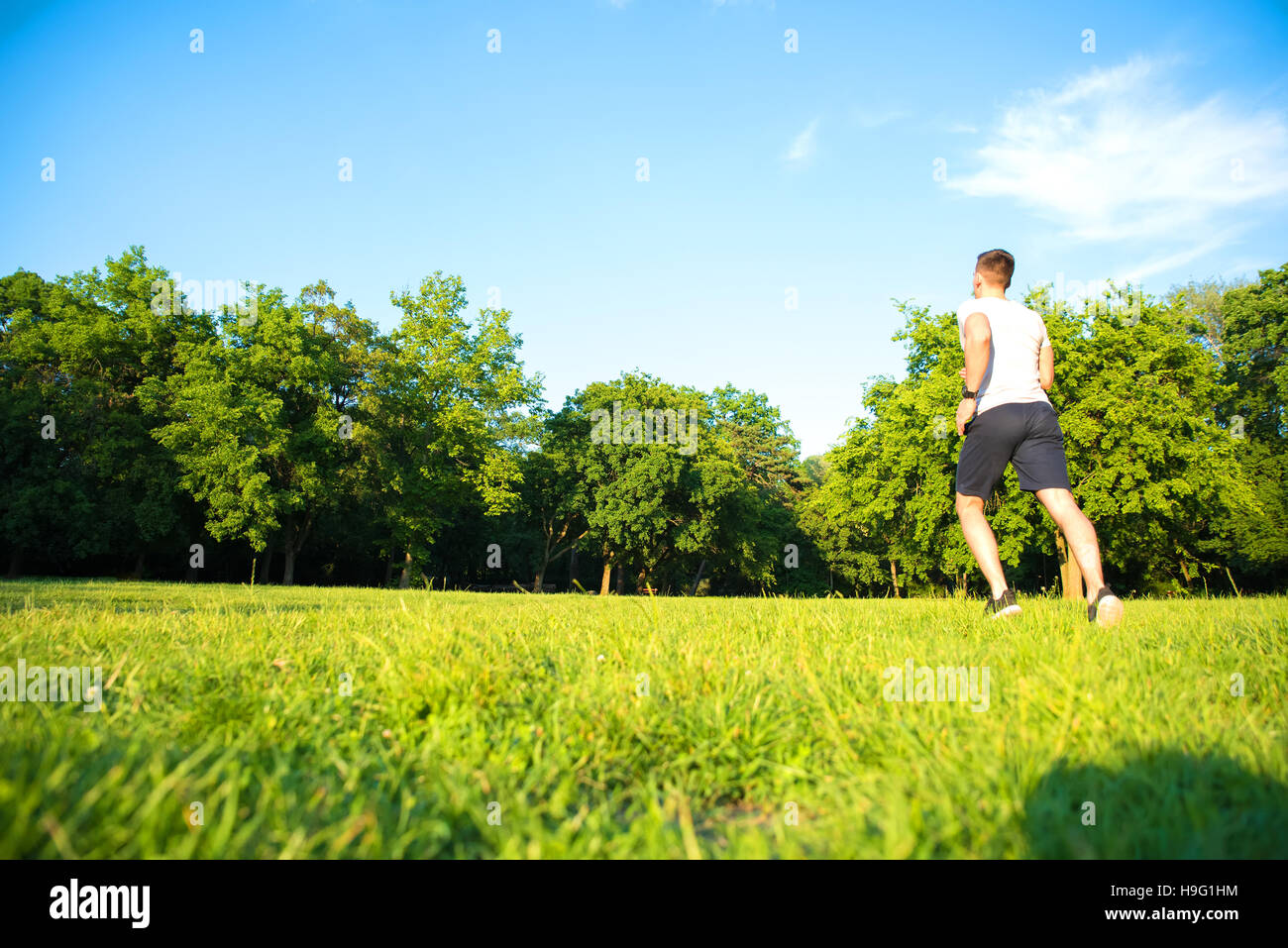 A handsome young man running on a summer evening in the sunset in a ...