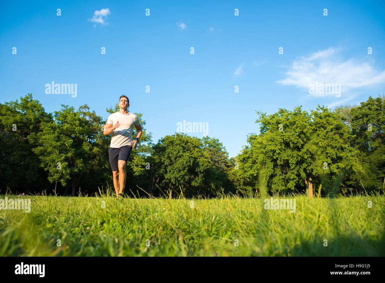 A handsome young man running on a summer evening in the sunset in a ...