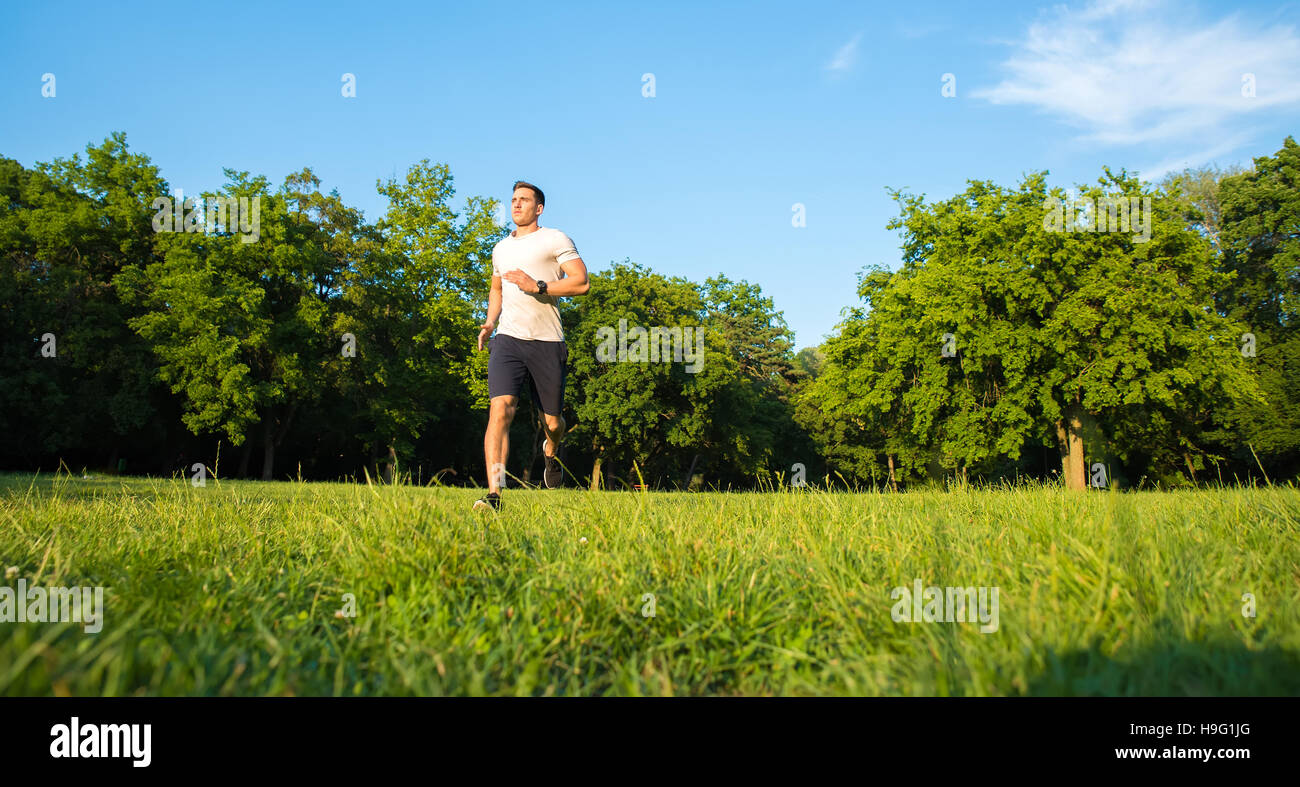 A handsome young man running on a summer evening in the sunset in a ...