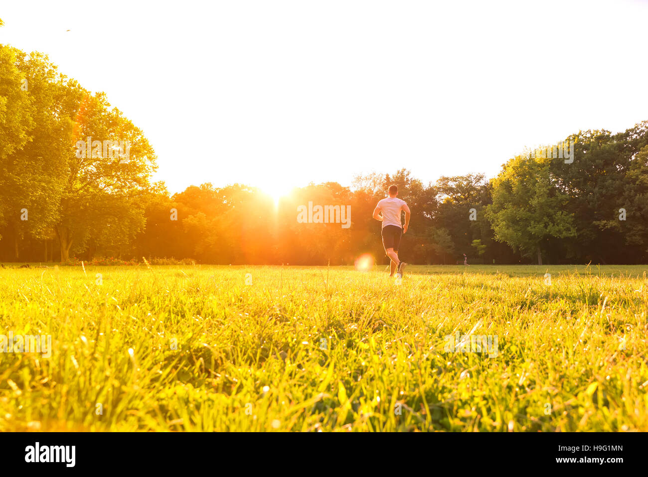 A handsome young man running on a summer evening in the sunset in a ...