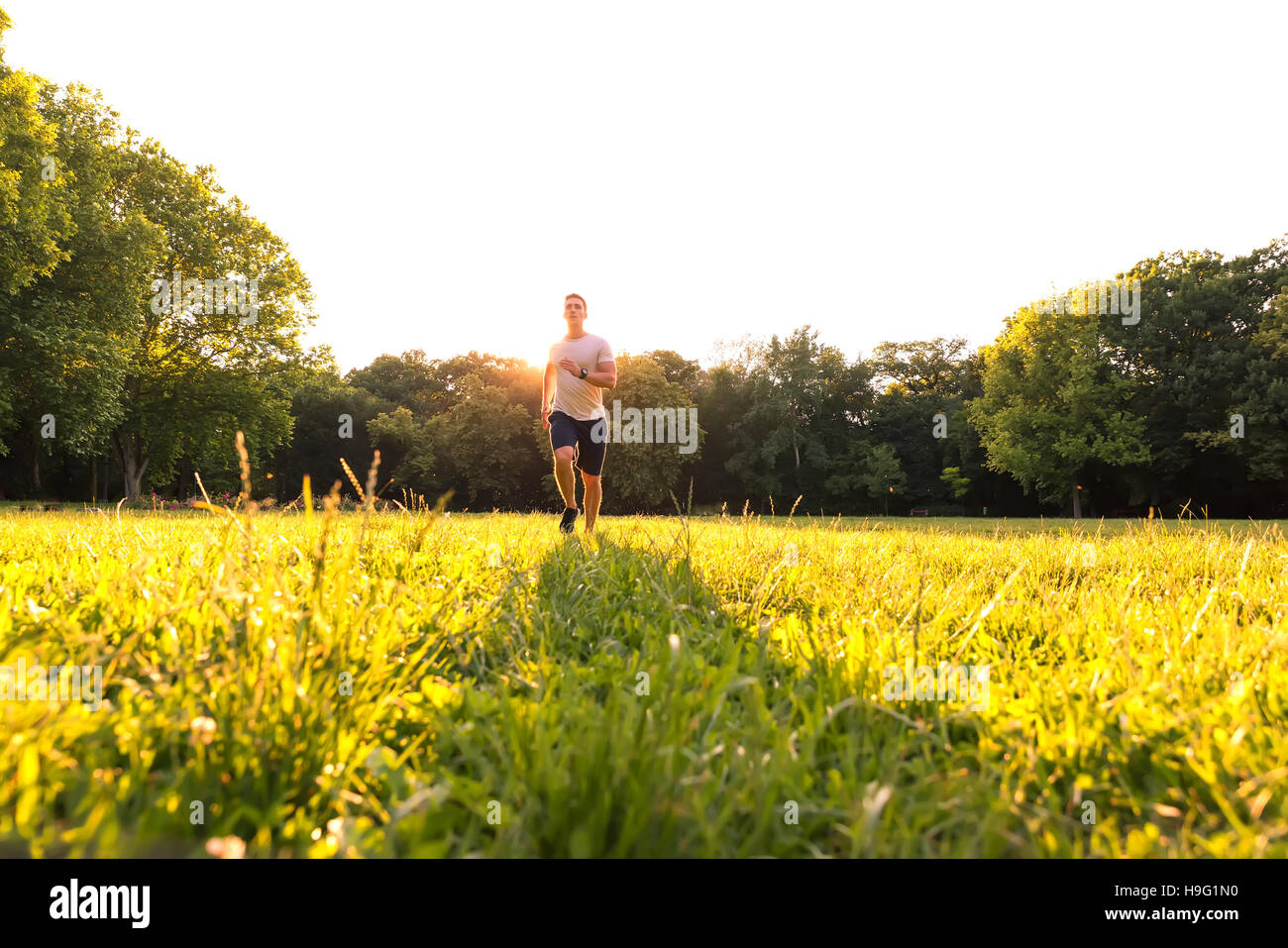 A handsome young man running on a summer evening in the sunset in a ...