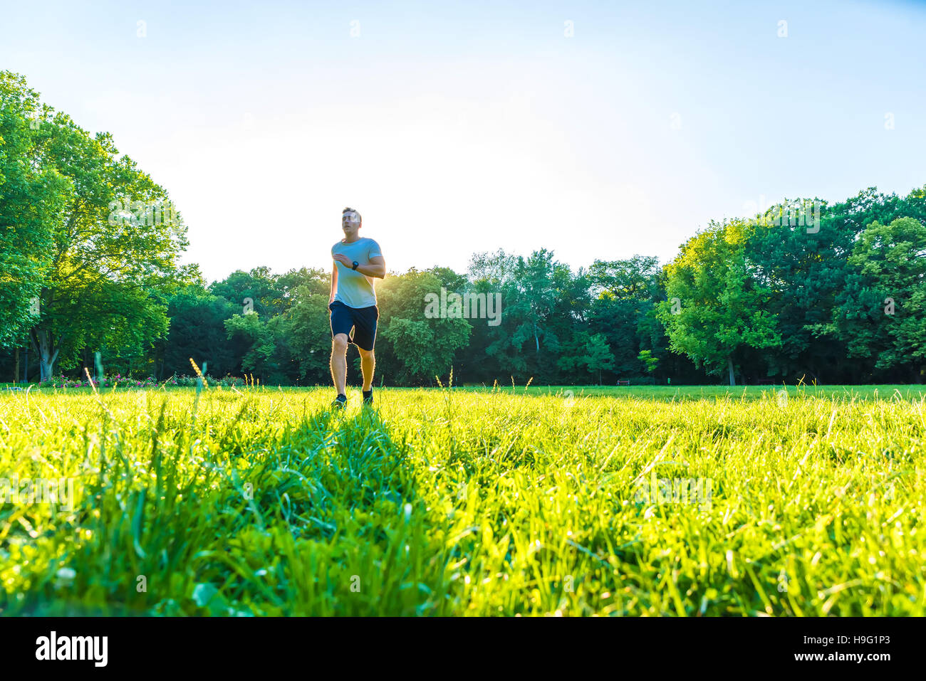 A handsome young man running on a summer evening in the sunset in a ...