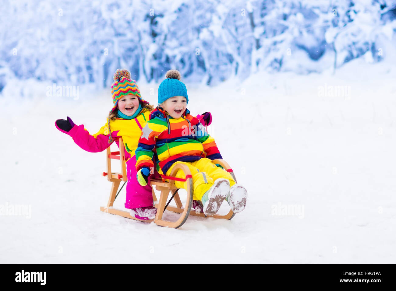 Little girl and boy enjoying sleigh ride. Child sledding. Toddler kid ...