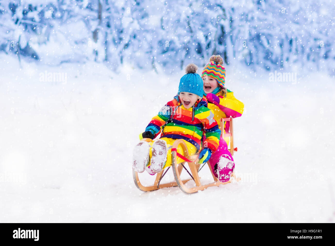 Little girl and boy enjoying sleigh ride. Child sledding. Toddler kid ...