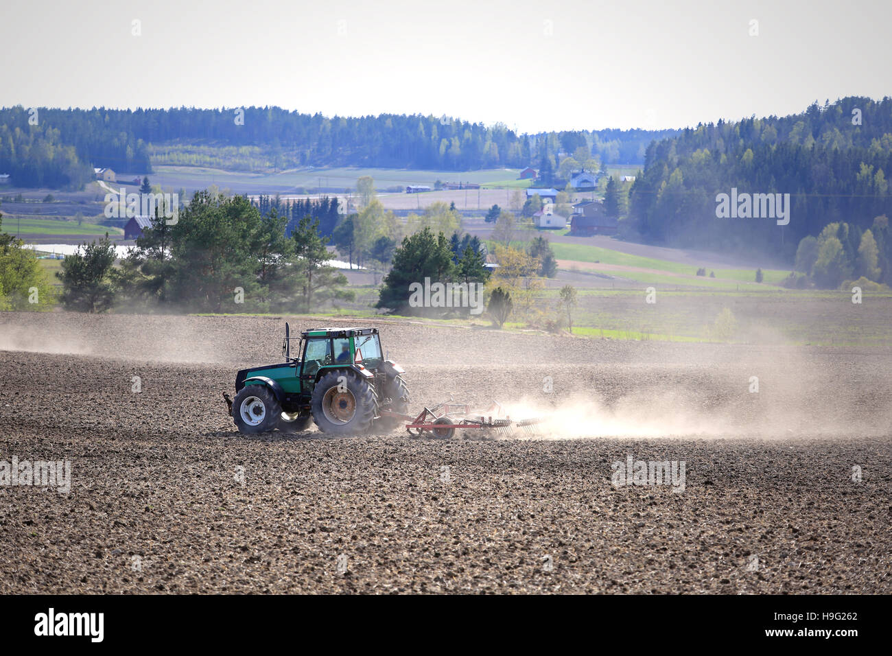 Country landscape with agricultural tractor cultivating the field on a ...