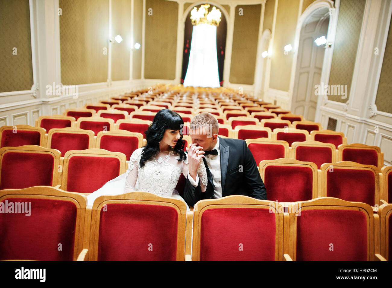 Wedding couple at hall amphitheater on red chairs Stock Photo - Alamy