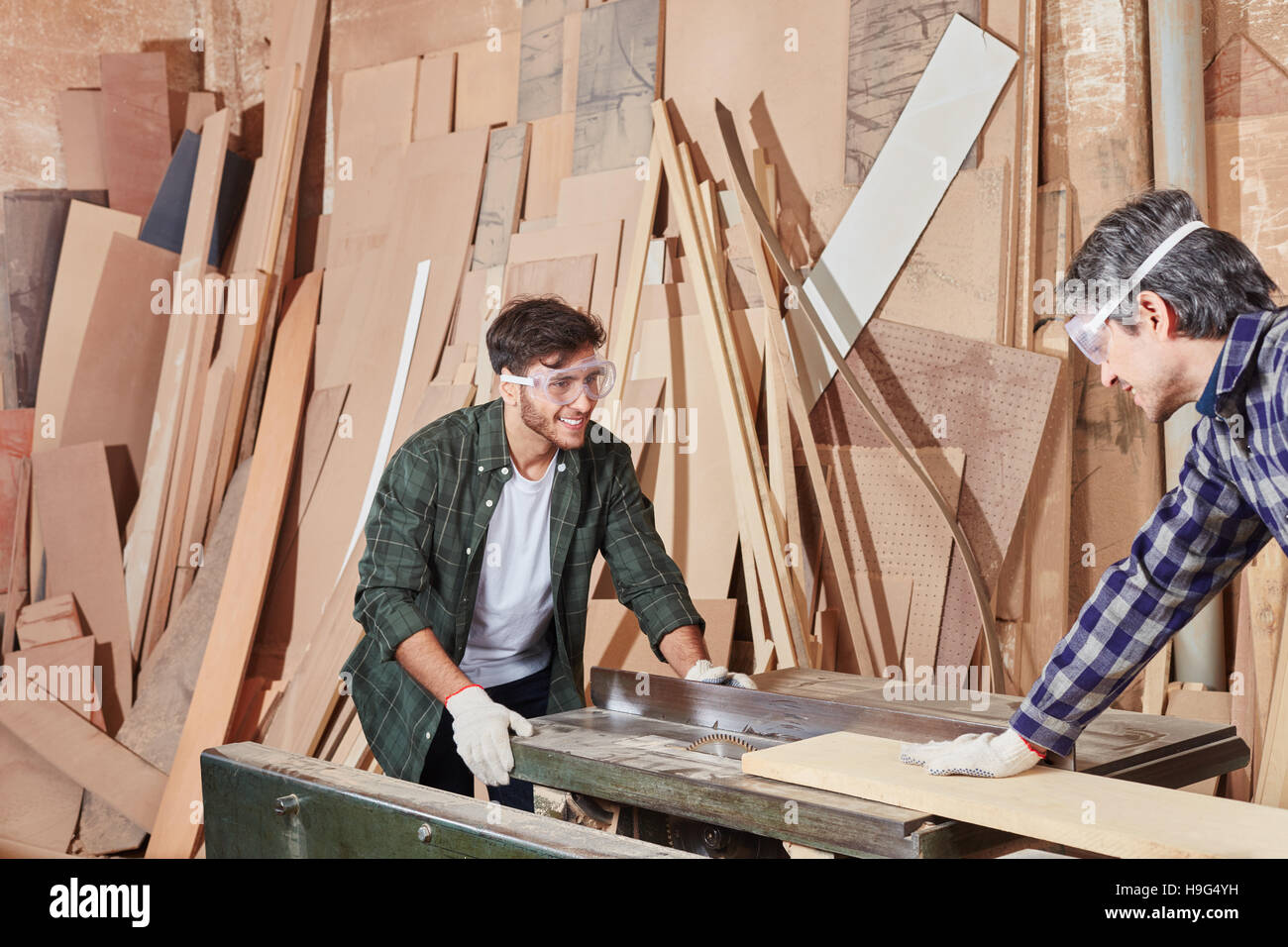 Two carpenters cooperating and woodworking with circular saw Stock ...