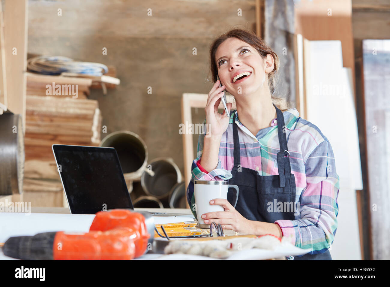 Woman at workshop calling on the phone and laughing Stock Photo - Alamy