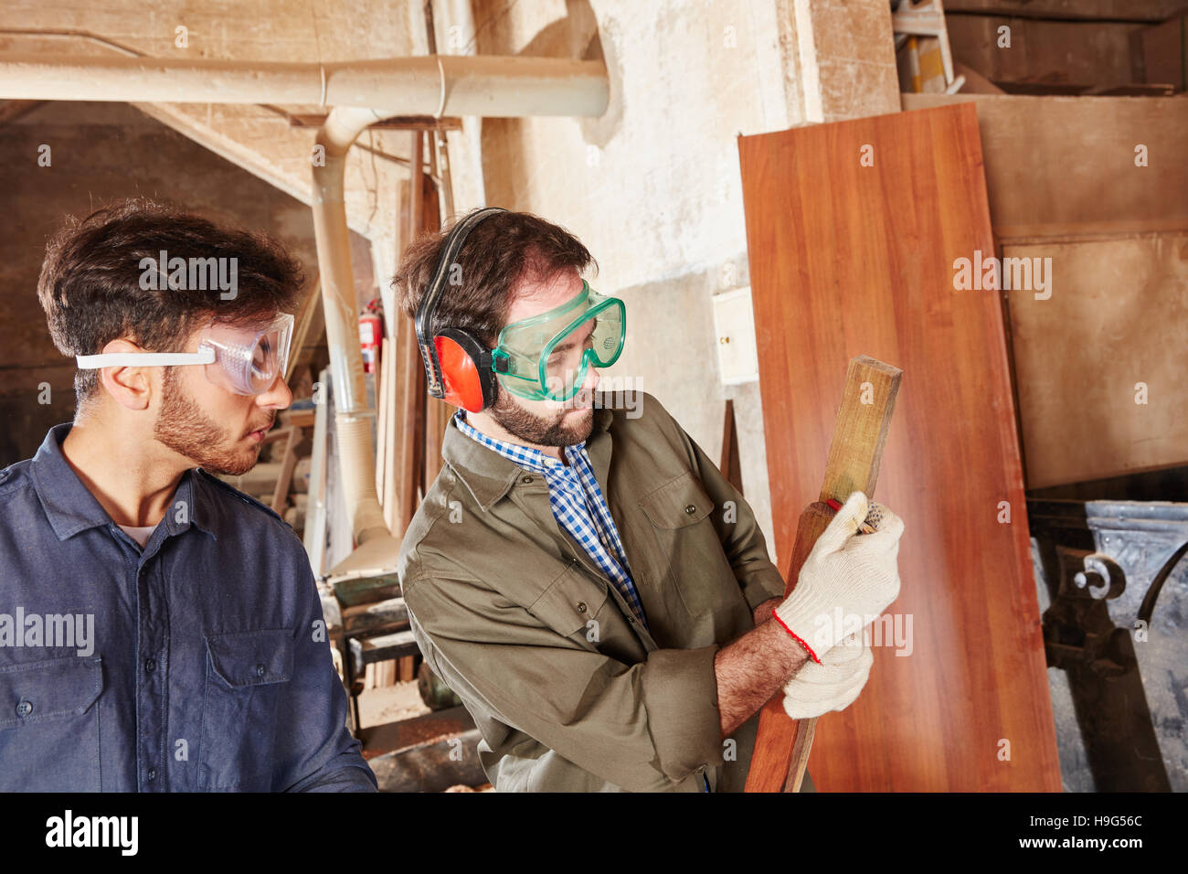Carpenters cooperating and measuring wood at carpentry workshop Stock ...
