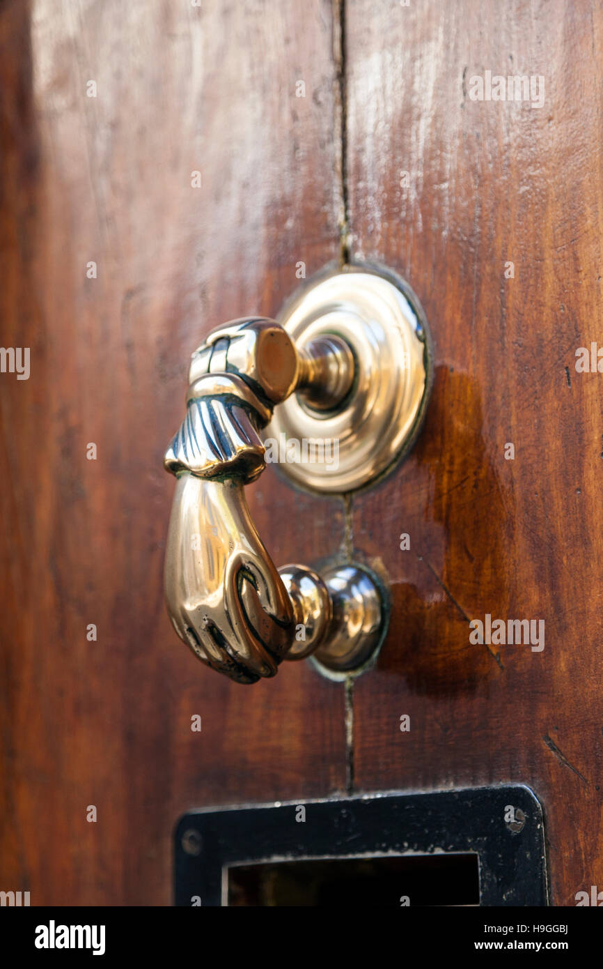 A gold hand-shaped door knocker Stock Photo - Alamy