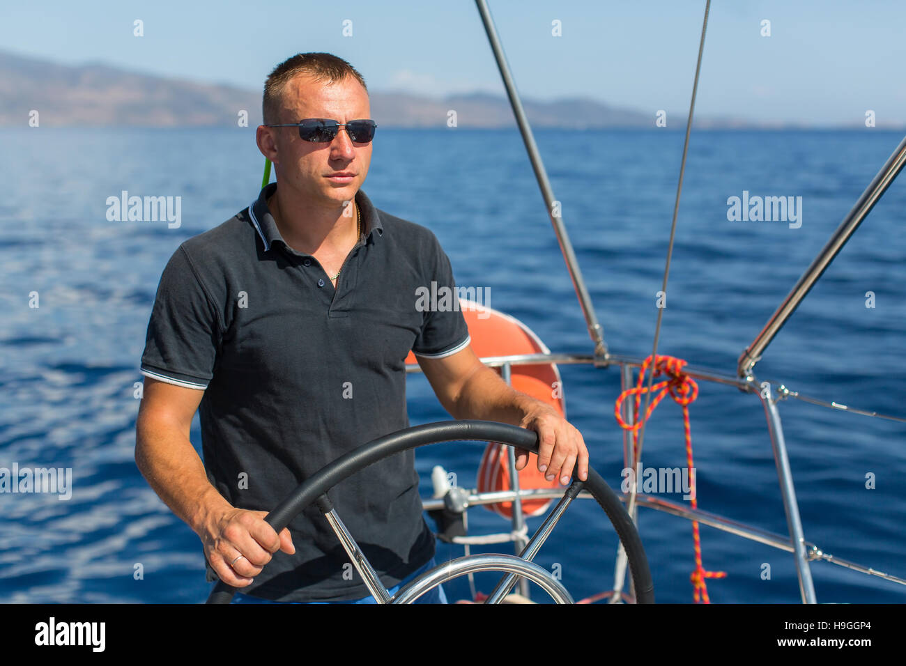 Man skipper at the helm sail boat, controls ship during sea yacht race ...