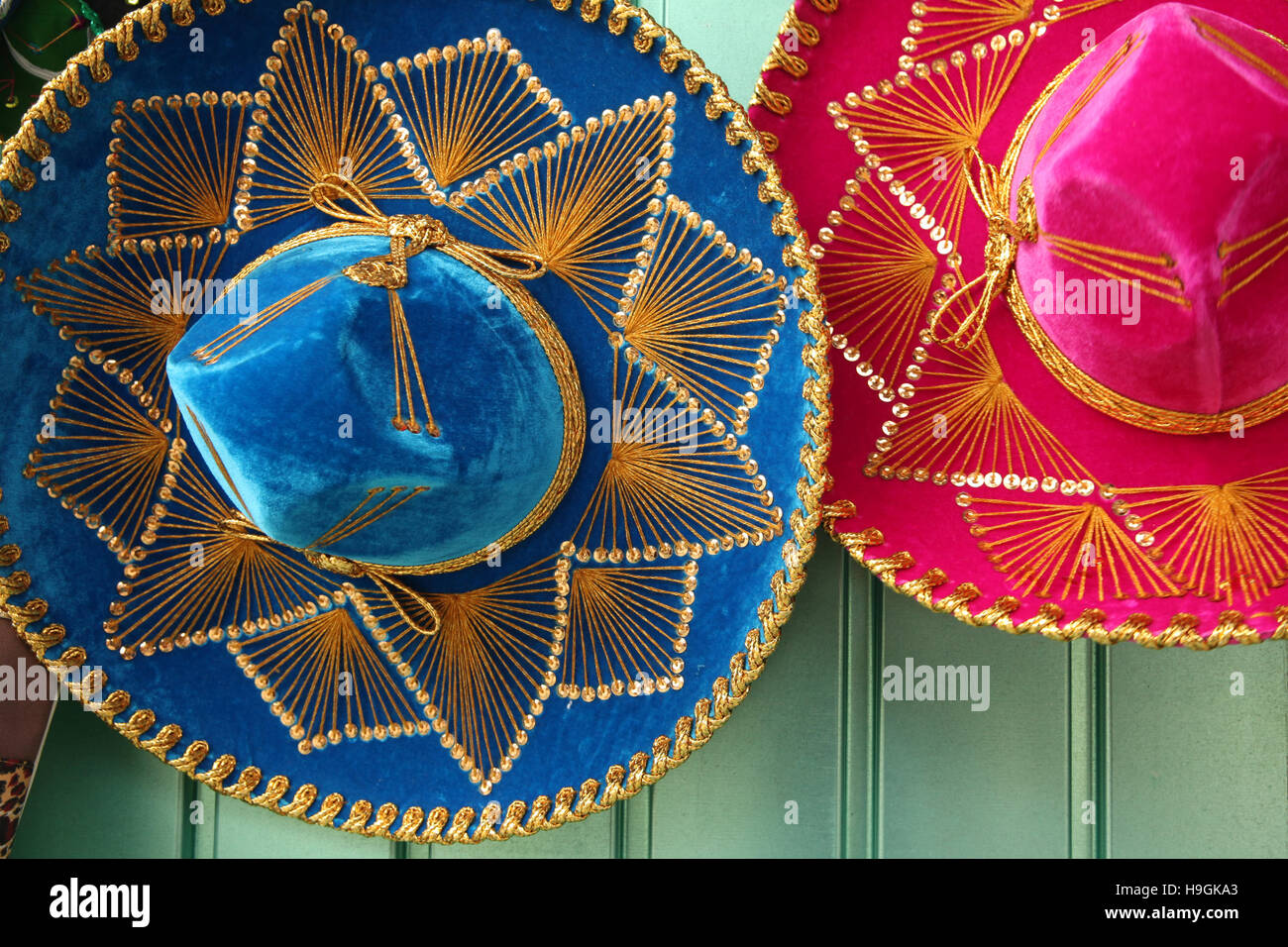 Colourful blue & pink Mexican hats or sombreros hanging on a green door ...